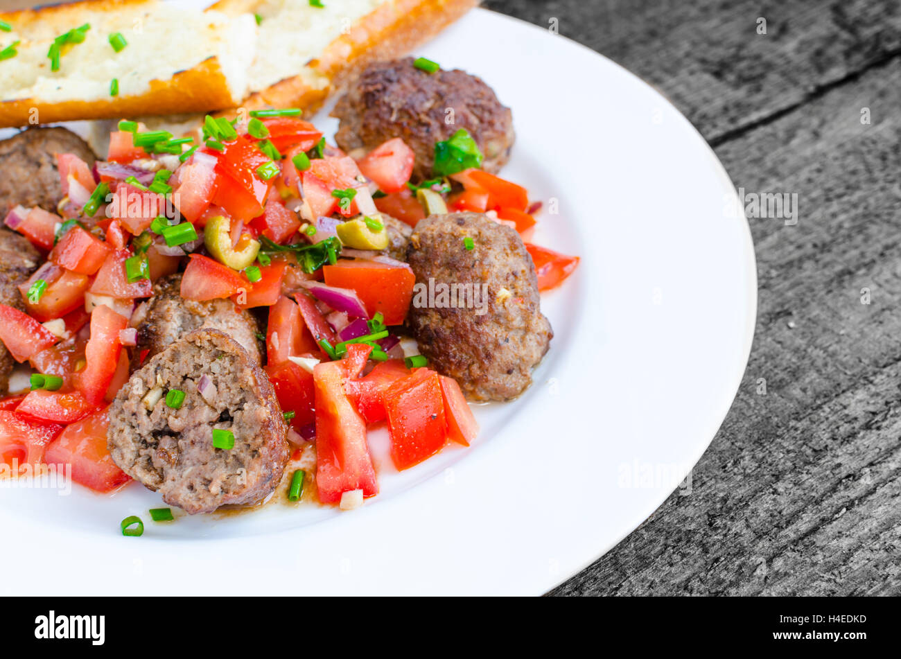 Meatballs with spicy tomato salsa, baked baguette and basil on top ...