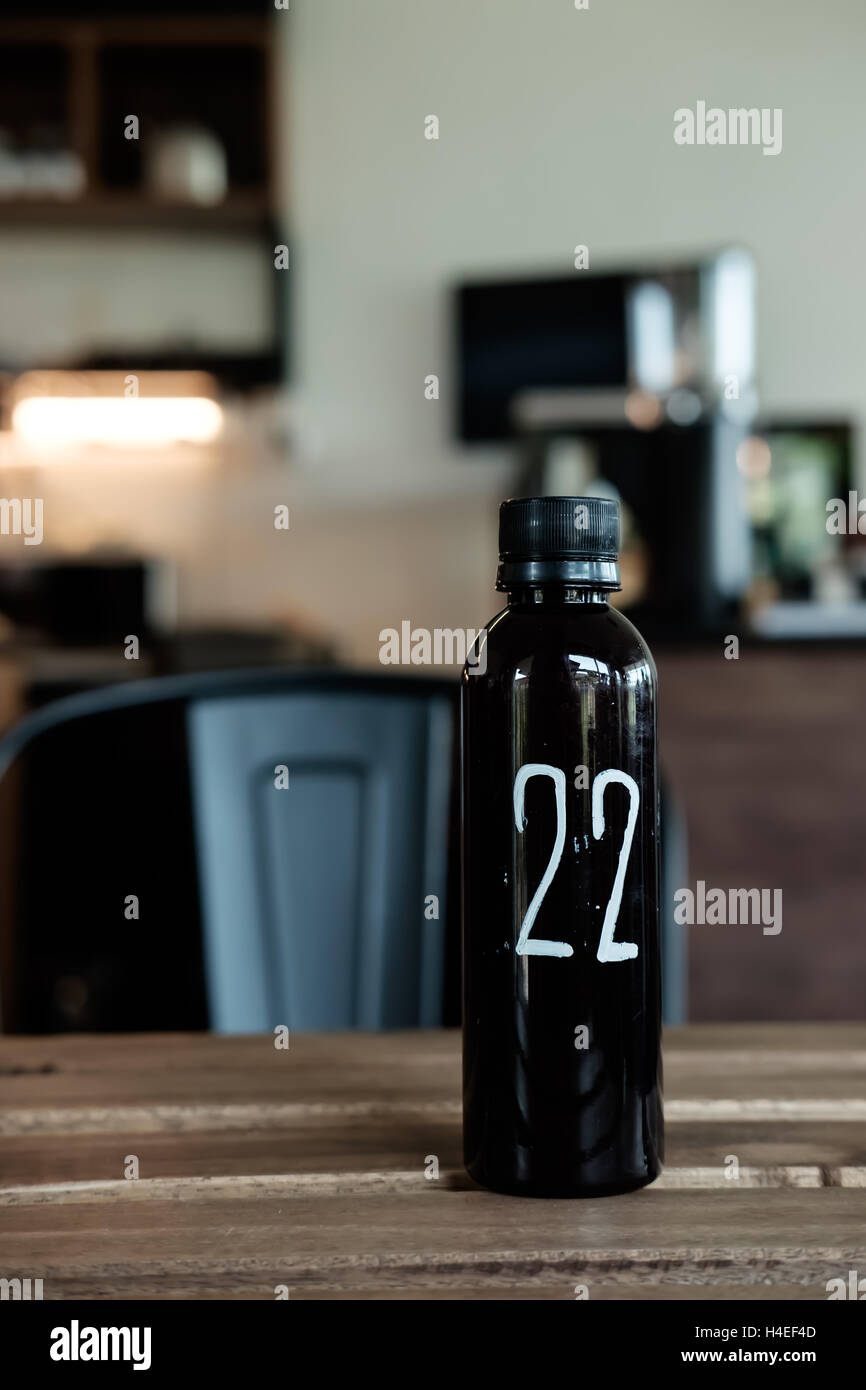 The number 22 written on a black bottle sitting on a wooden cafe table ...