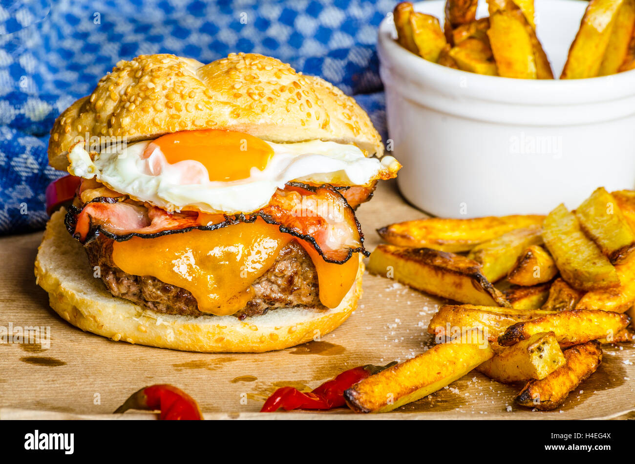 Homemade burger with fried egg and spicy fries on wood board Stock ...