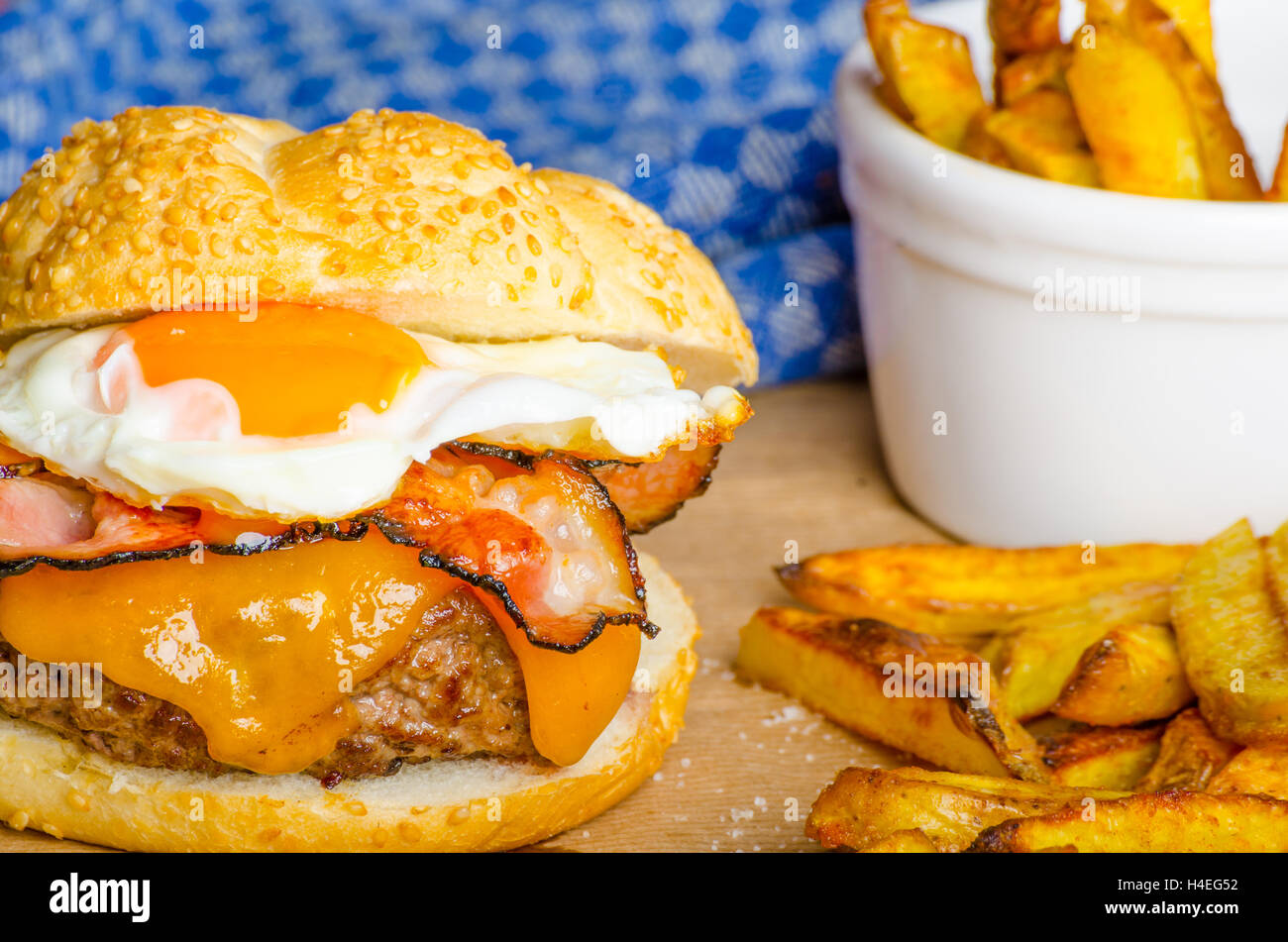 Homemade burger with fried egg and spicy fries on wood board Stock ...