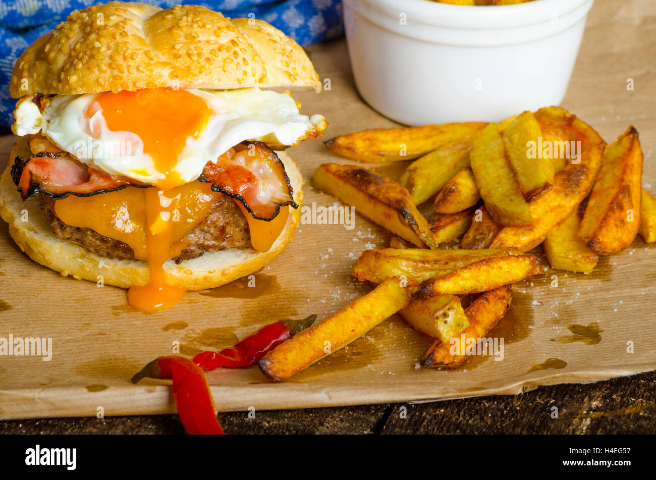 Homemade burger with fried egg and spicy fries on wood board Stock ...