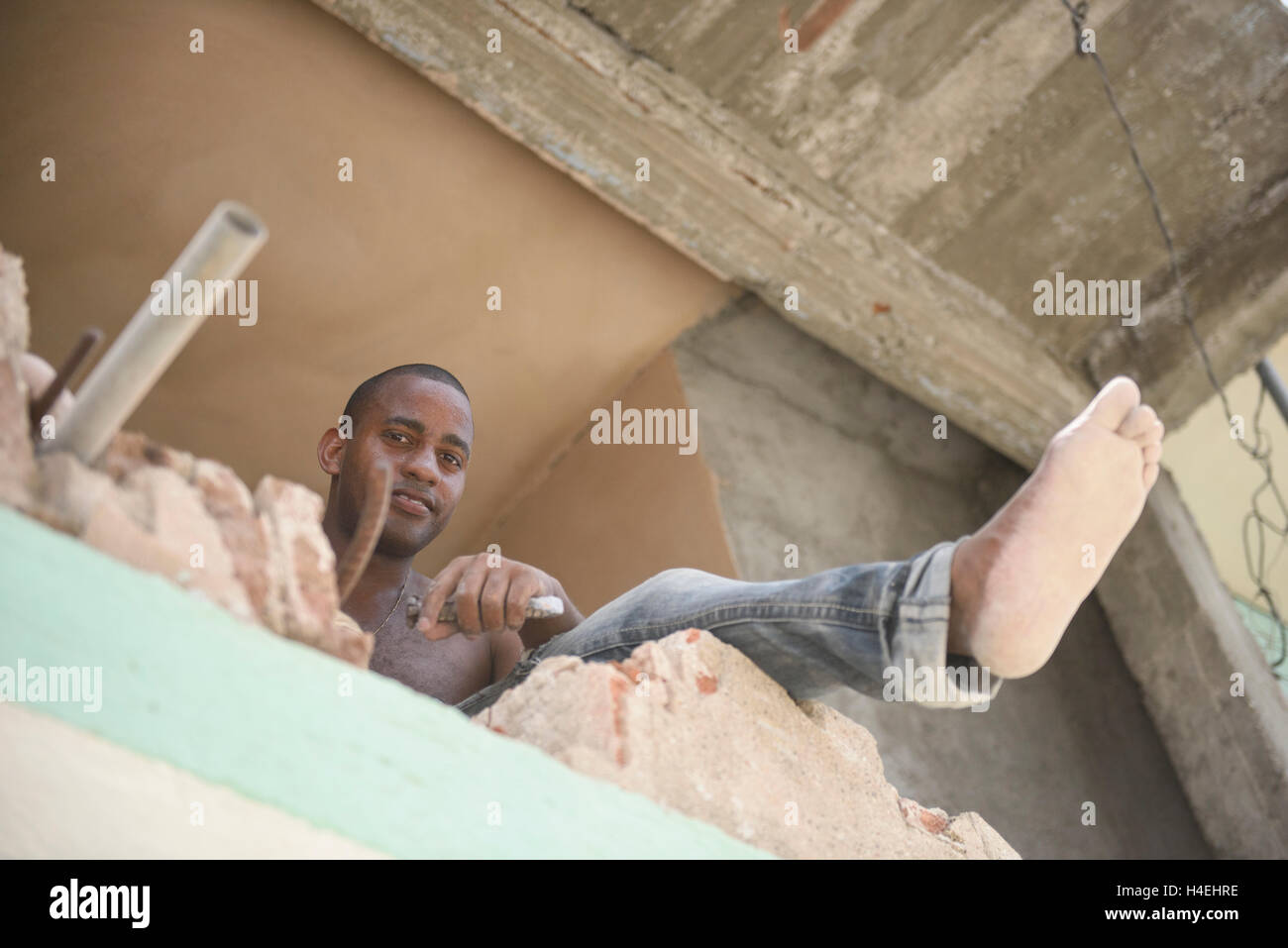 Builder is sitting with his barefoot stretched forward during the ...
