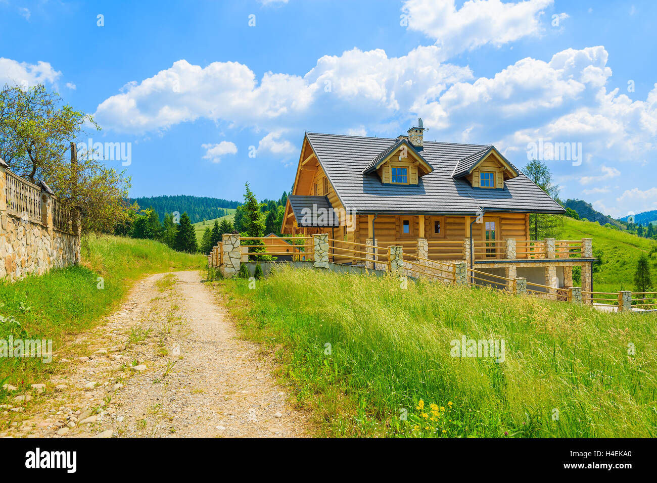 Rural road to wooden traditional mountain house on green field in ...