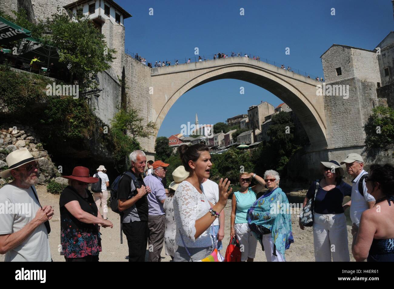 A tour guide talks to tourists in front of the Stari Most bridge ...