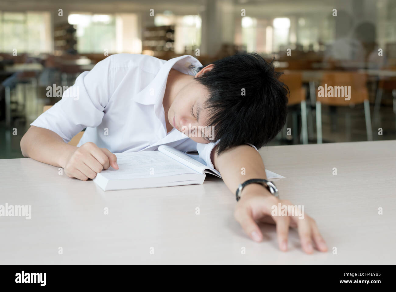 Tired Asian student or Asian young man with books sleeping in library ...