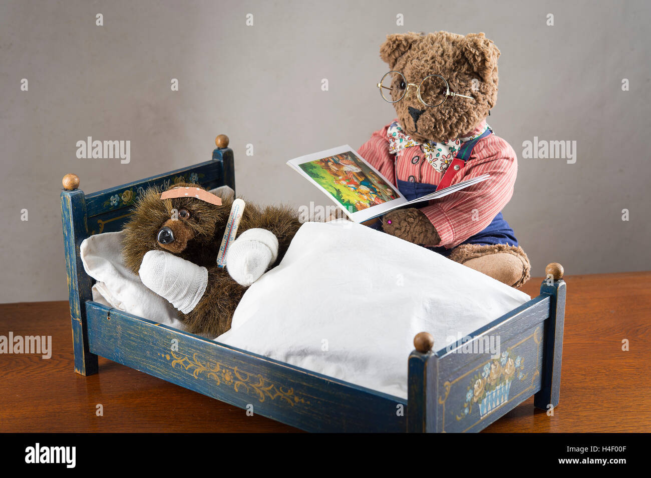Sick Teddy Bear with bandaged paws and head, holding thermometer, in an ...