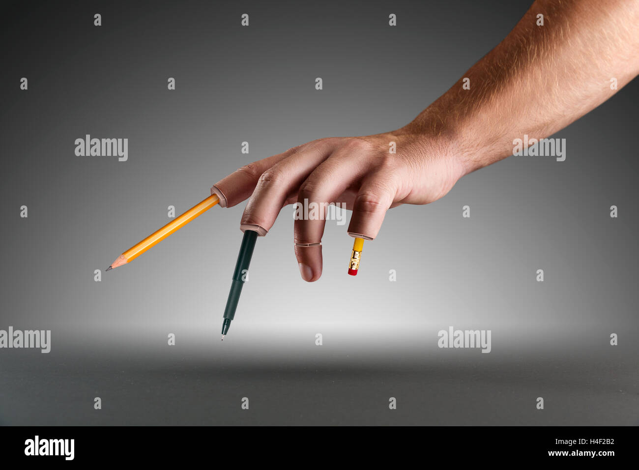 Hand with pen and pencils instead of fingers Stock Photo - Alamy
