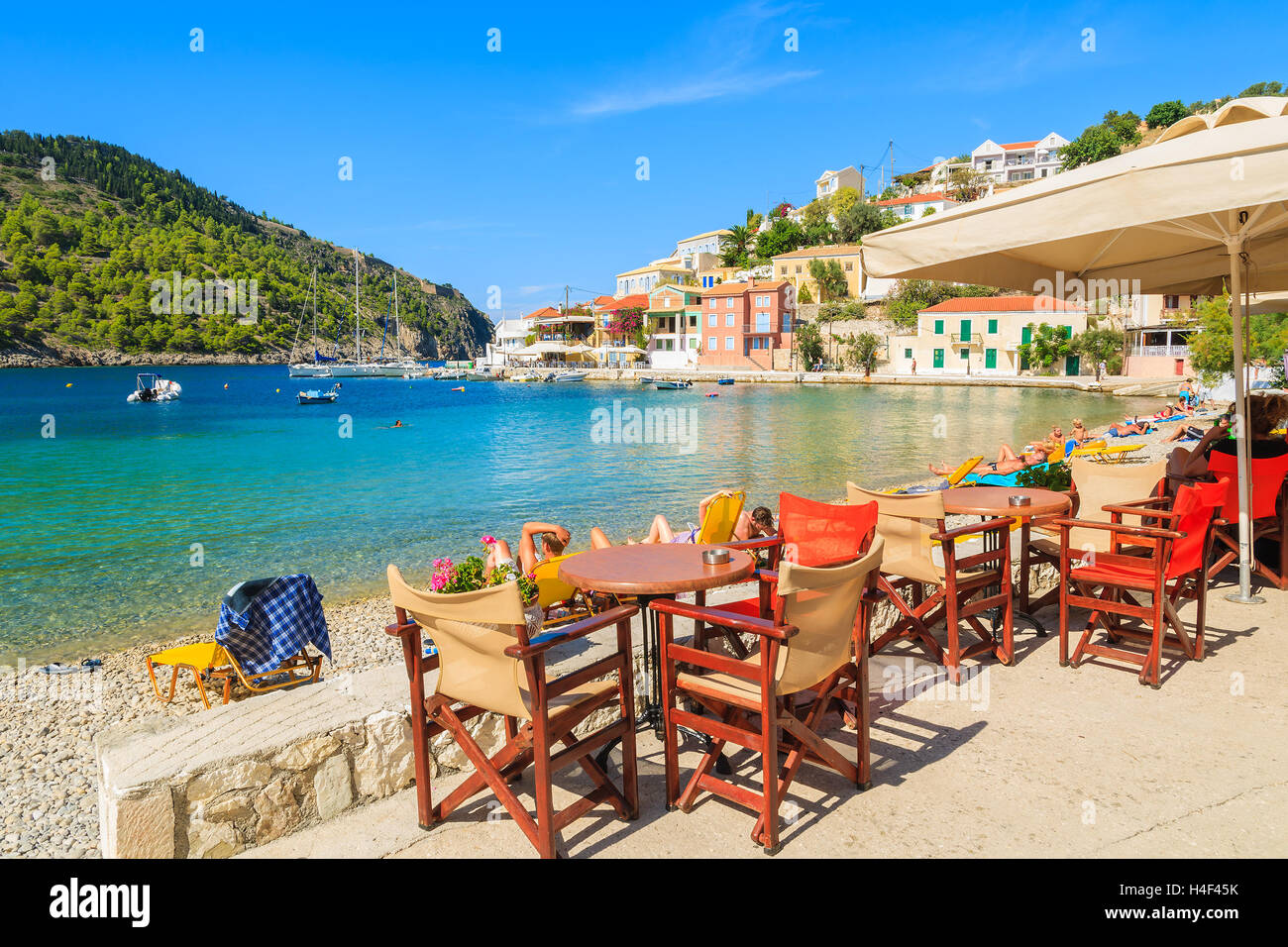 Tables with chairs in Greek tavern on beautiful beach in Assos village ...