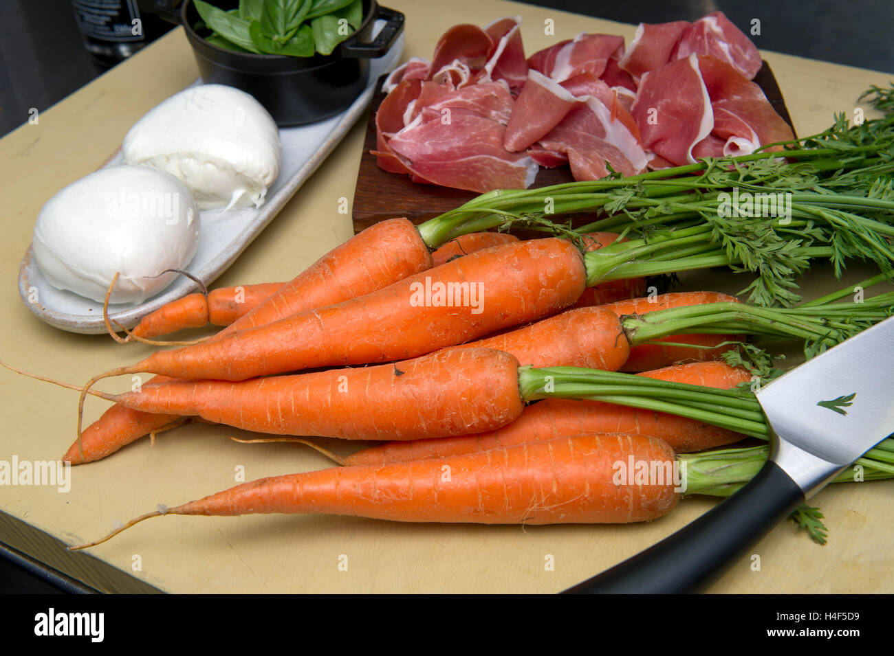 Raw carrots with a knife and carrots cooking in a shallow frying pan. a ...
