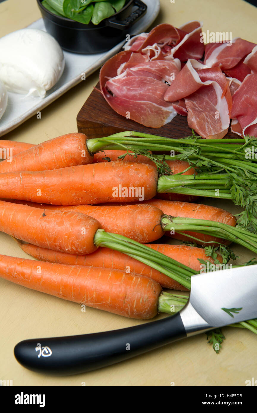 Raw carrots with a knife and carrots cooking in a shallow frying pan. a ...
