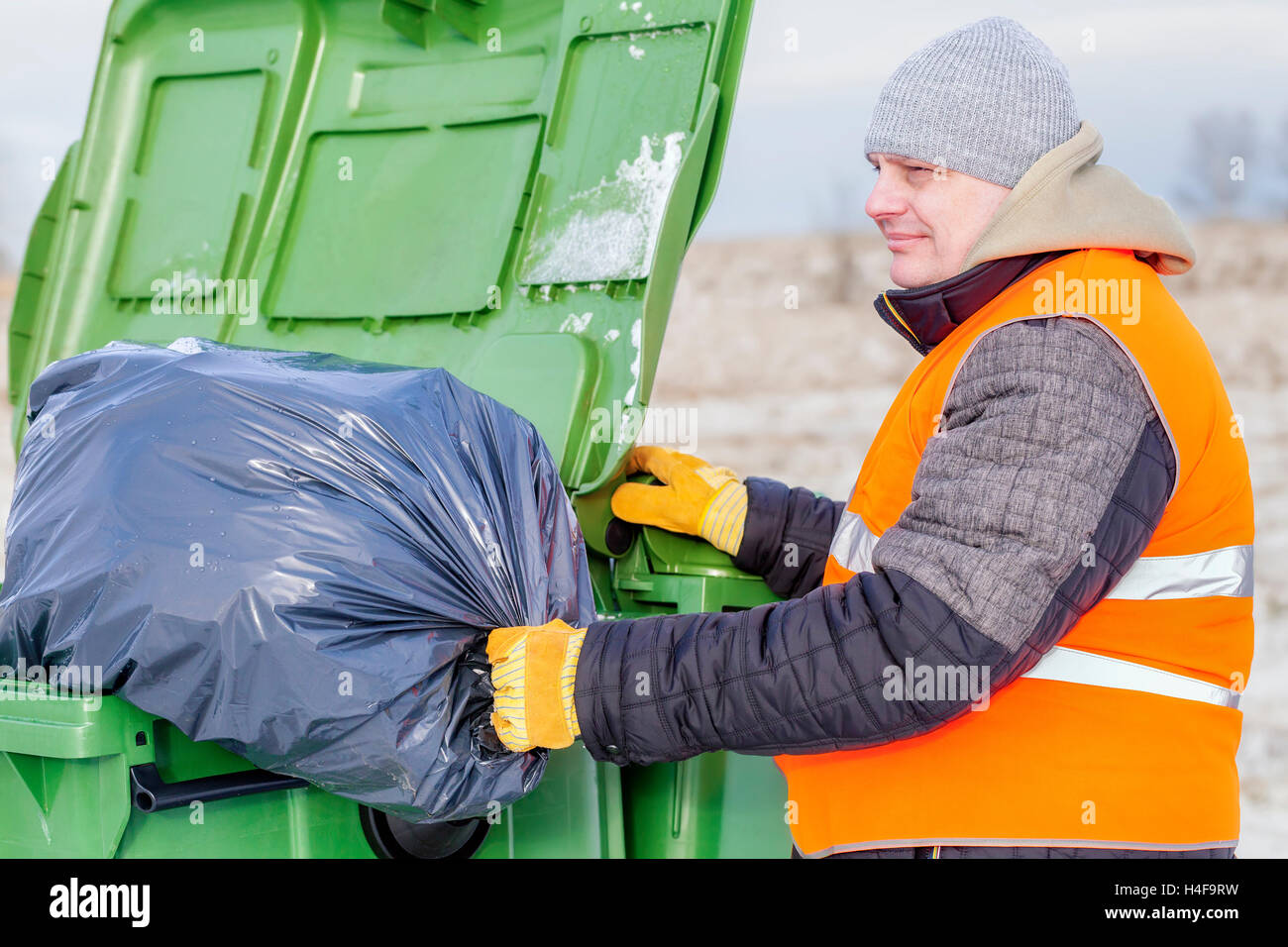 Worker with garbage bag near the container Stock Photo - Alamy