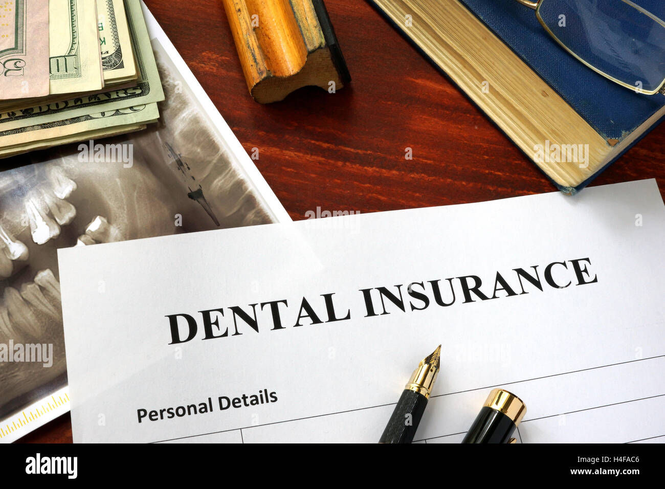 Dental insurance policy on a table with a book Stock Photo - Alamy