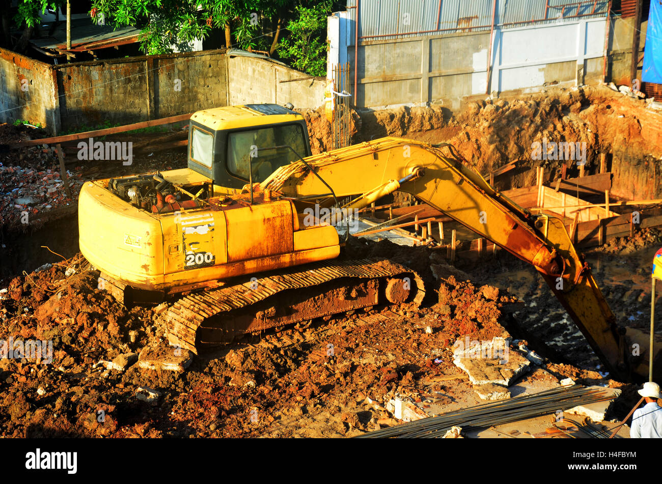 Old Backhoe and Builder worker in safety protective equipment with ...