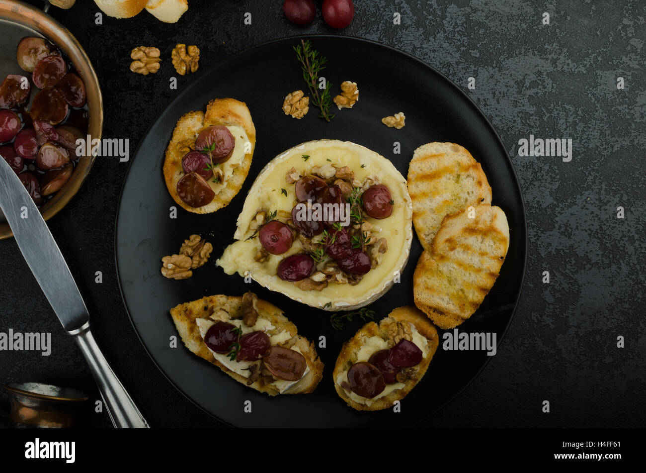 Brie cheese baked with nuts and grapes, tasty and crispy baguette and ...