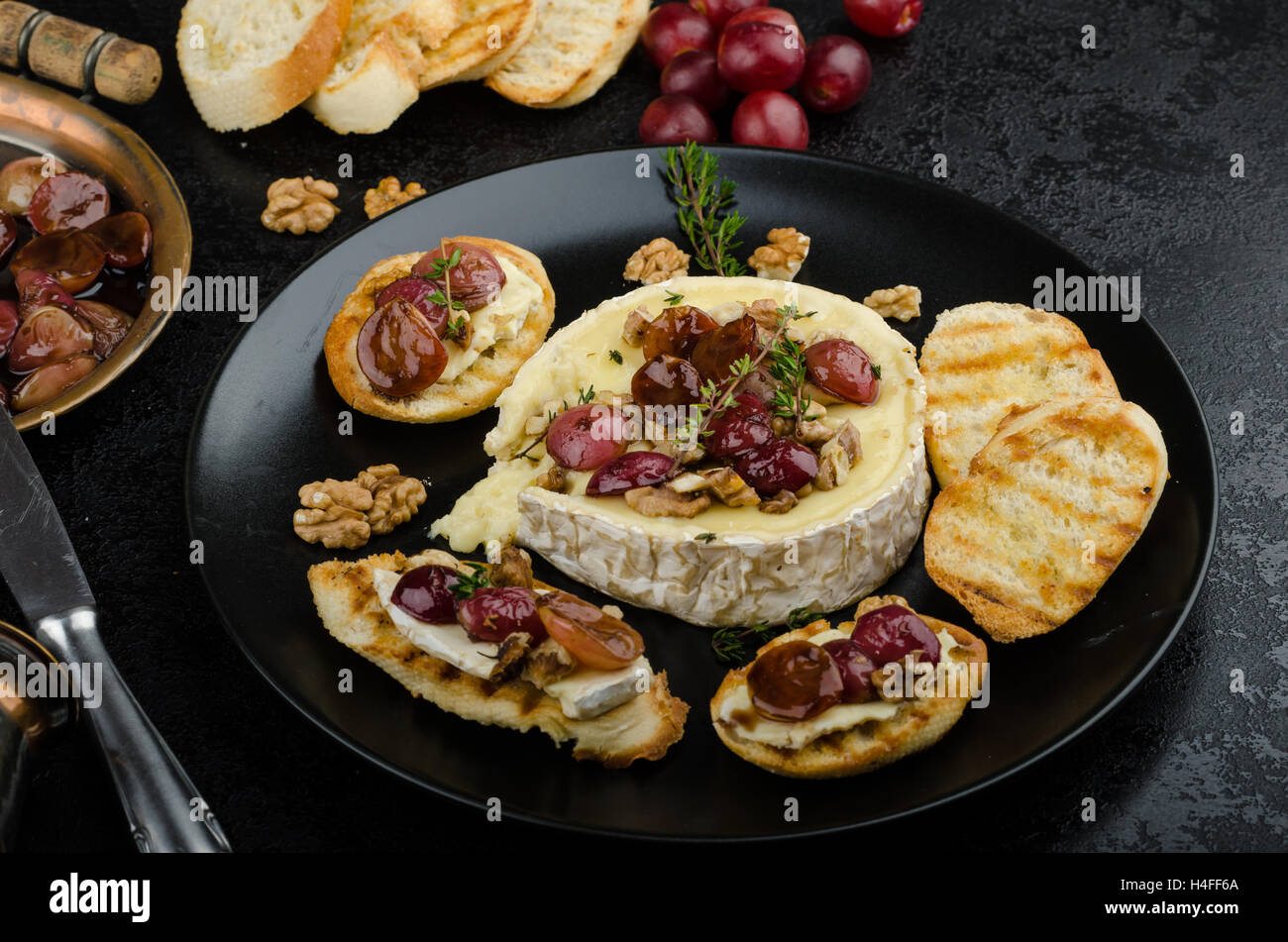 Brie cheese baked with nuts and grapes, tasty and crispy baguette and ...