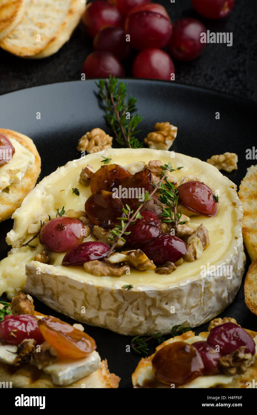 Brie cheese baked with nuts and grapes, tasty and crispy baguette and ...
