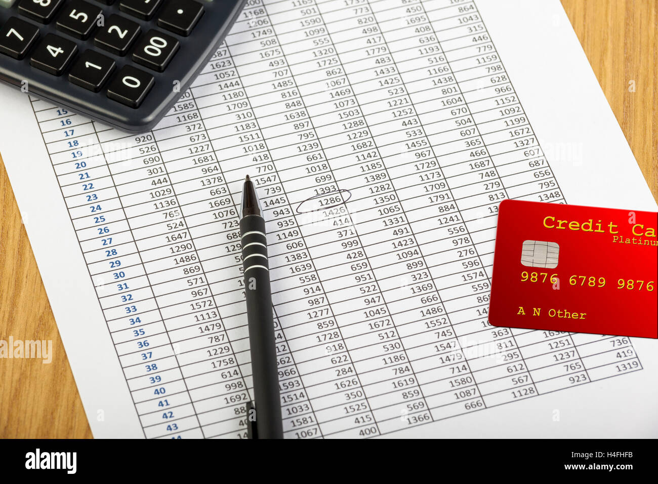 Red credit card laying on a spreadsheet printout with circled entries ...