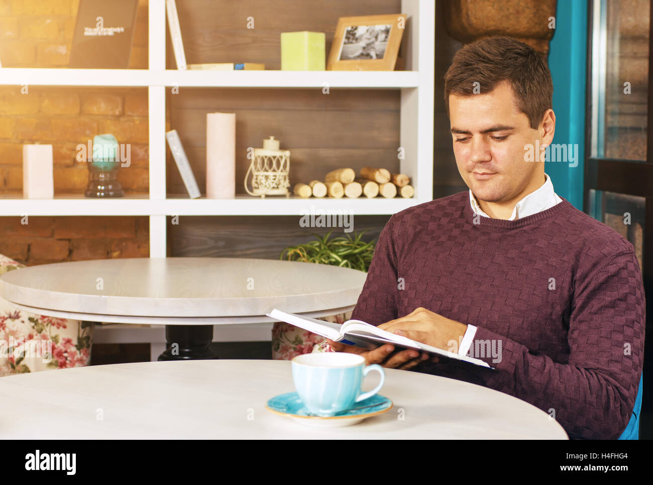 Young man sitting in cafe and reading a book Stock Photo - Alamy