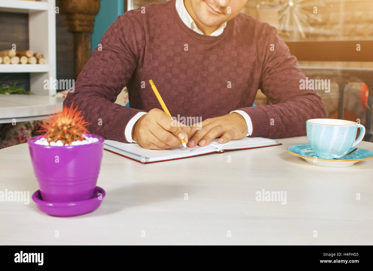 Man holding pencil and writing on a paper in the diary Stock Photo - Alamy