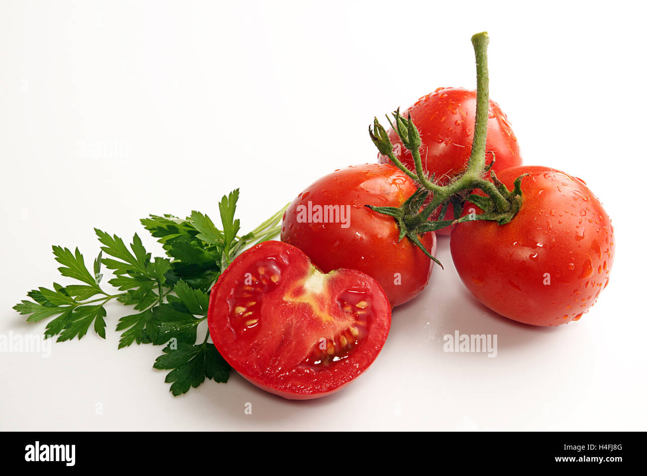 Branch of fresh ripe tomatoes and half of cutted tomato on white ...