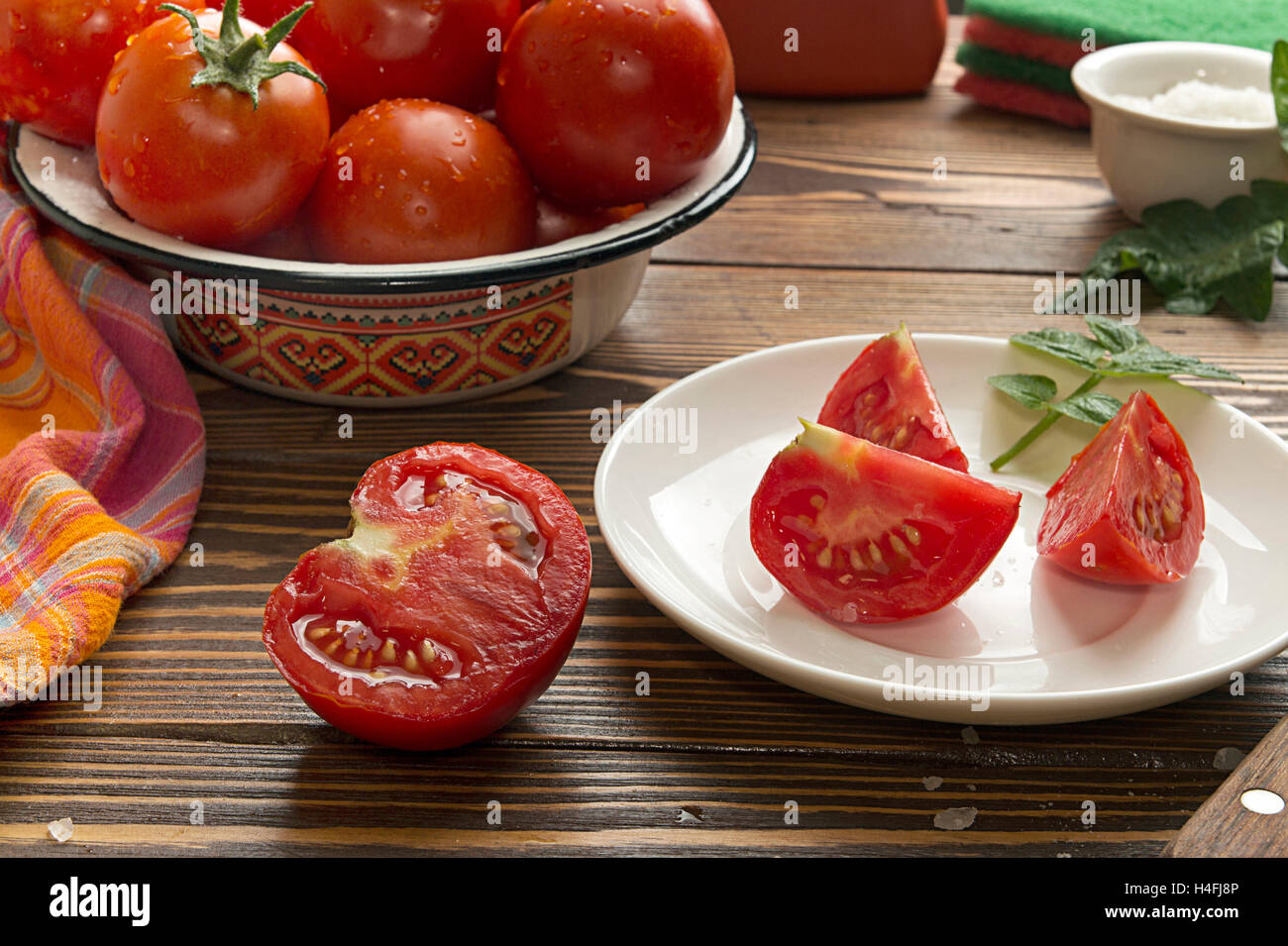 Fresh ripe tomatoes in yellow bowl, half of cutted tomato Stock Photo ...