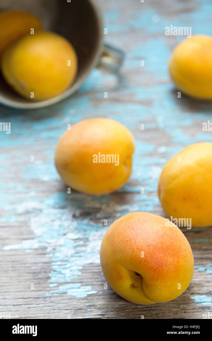 Apricots rolled out on a rustic wooden surface from aluminum mug Stock ...