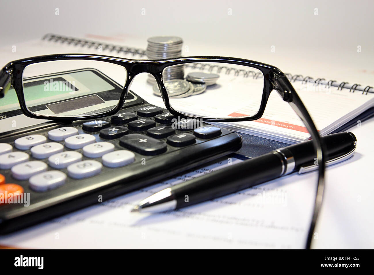 Glasses, calculator, coins, and pen on desk Stock Photo - Alamy