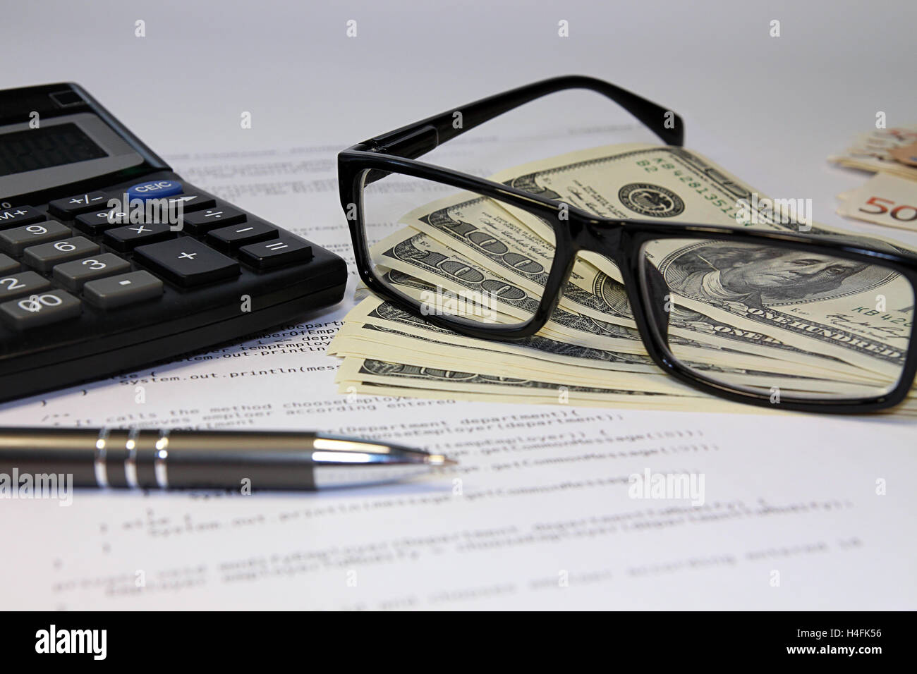 Glasses, calculator, bancnote and pen on document with programmer code ...