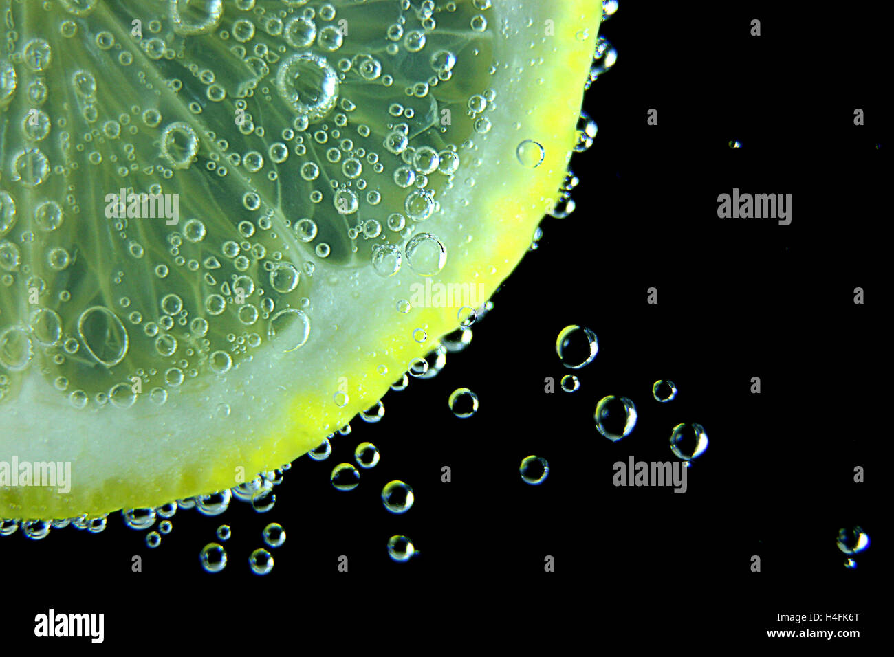 Slice of the lemon with bubbles on the black background Stock Photo - Alamy