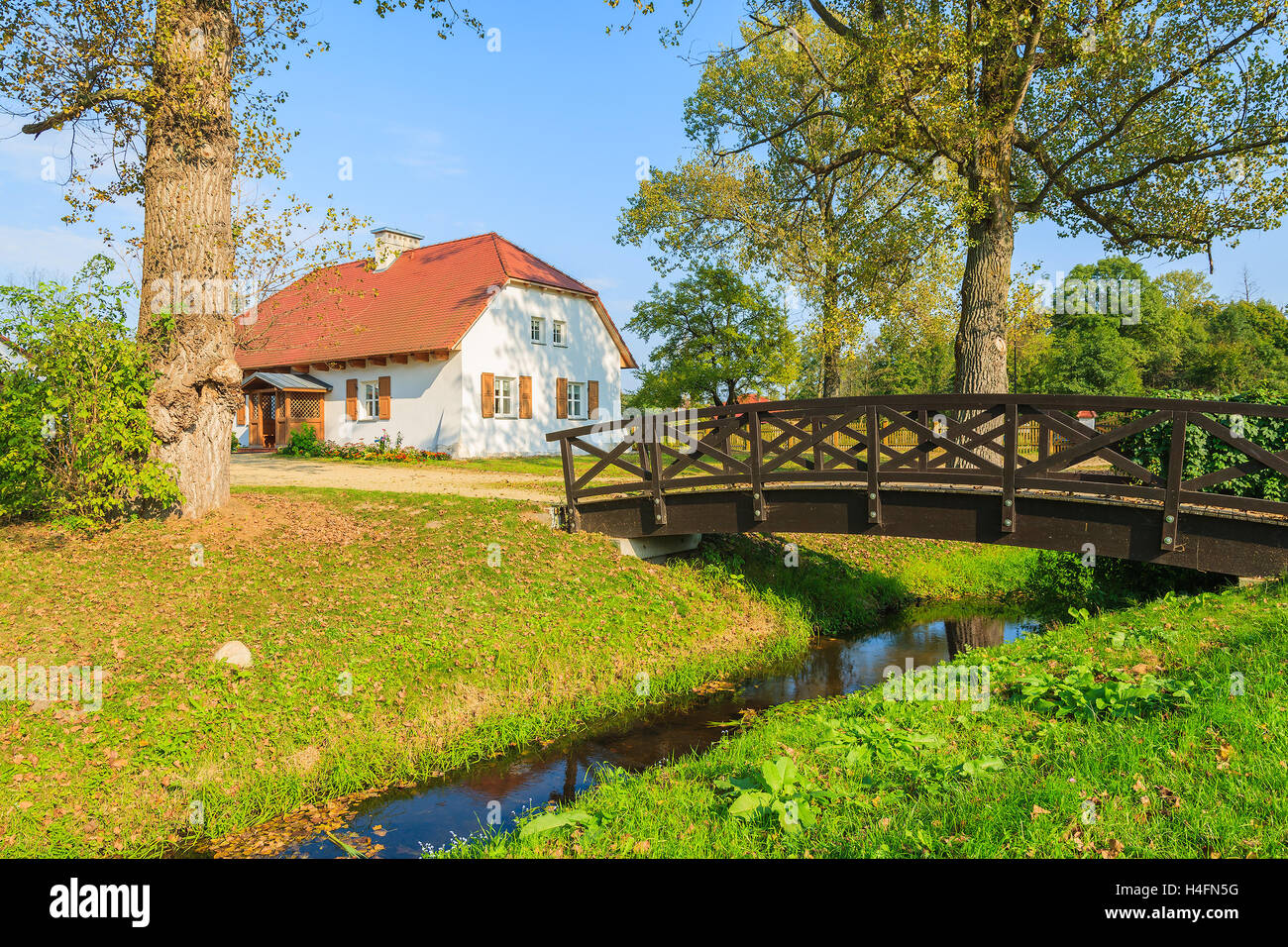 Wooden footbridge over small river and traditional cottage house in ...