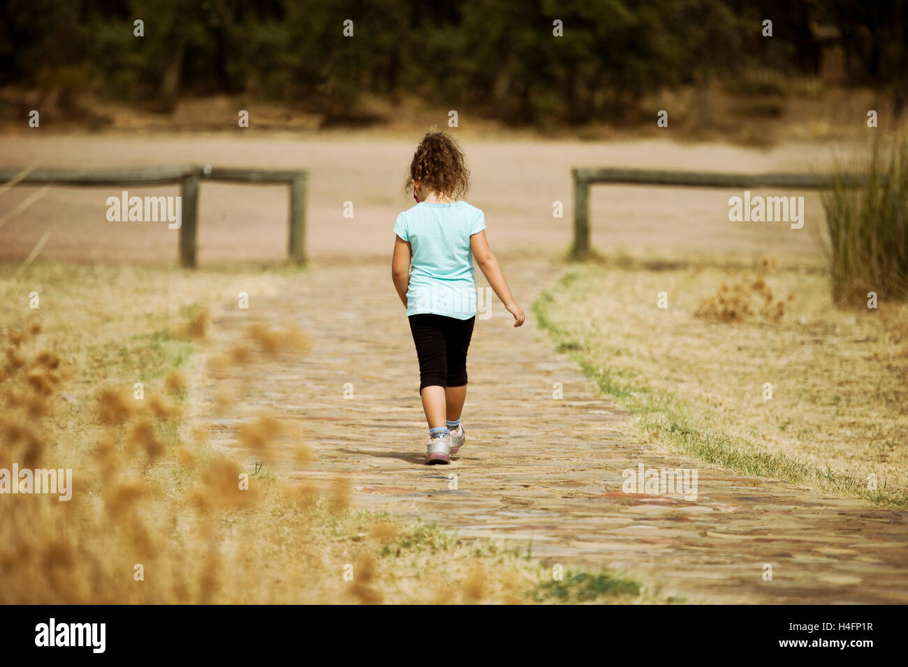 Back view of unrecognizable lonely girl walking away on stone ground in ...