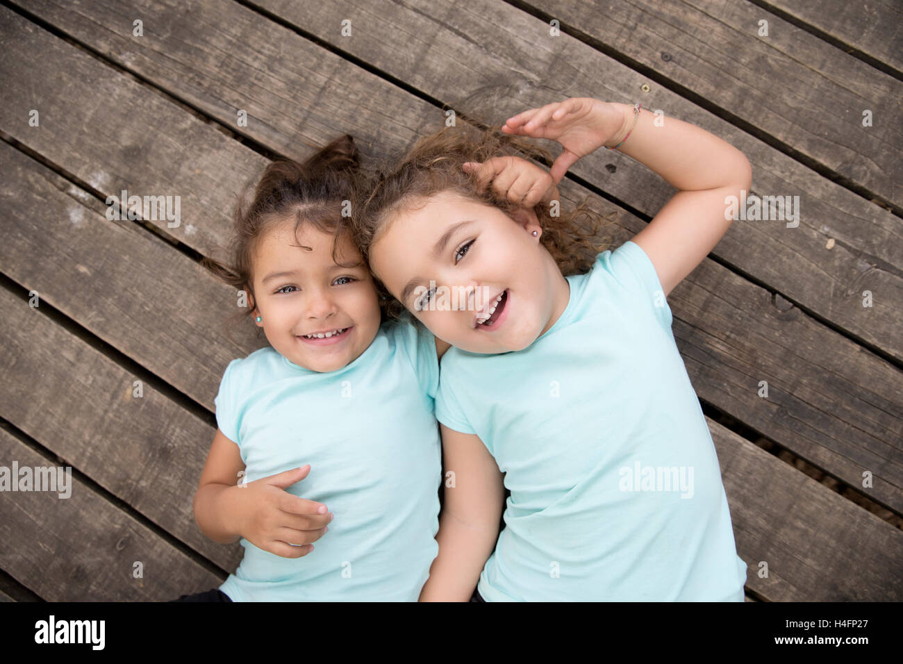 Top view portrait of cute smiling sisters in similar blue t-shirts ...