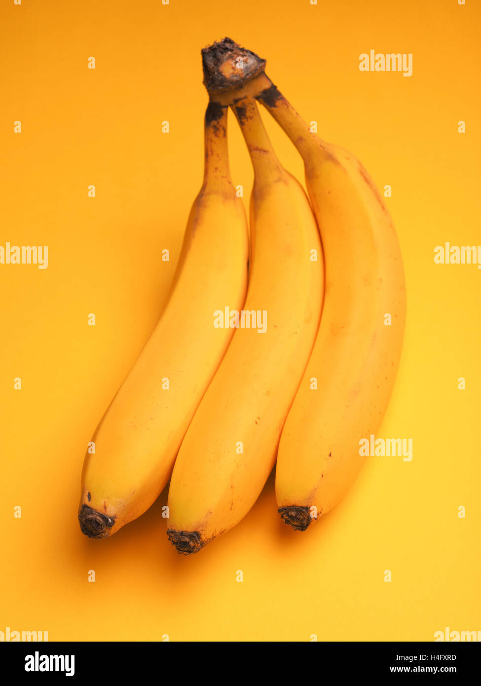 Three fresh bananas on a yellow background Stock Photo - Alamy