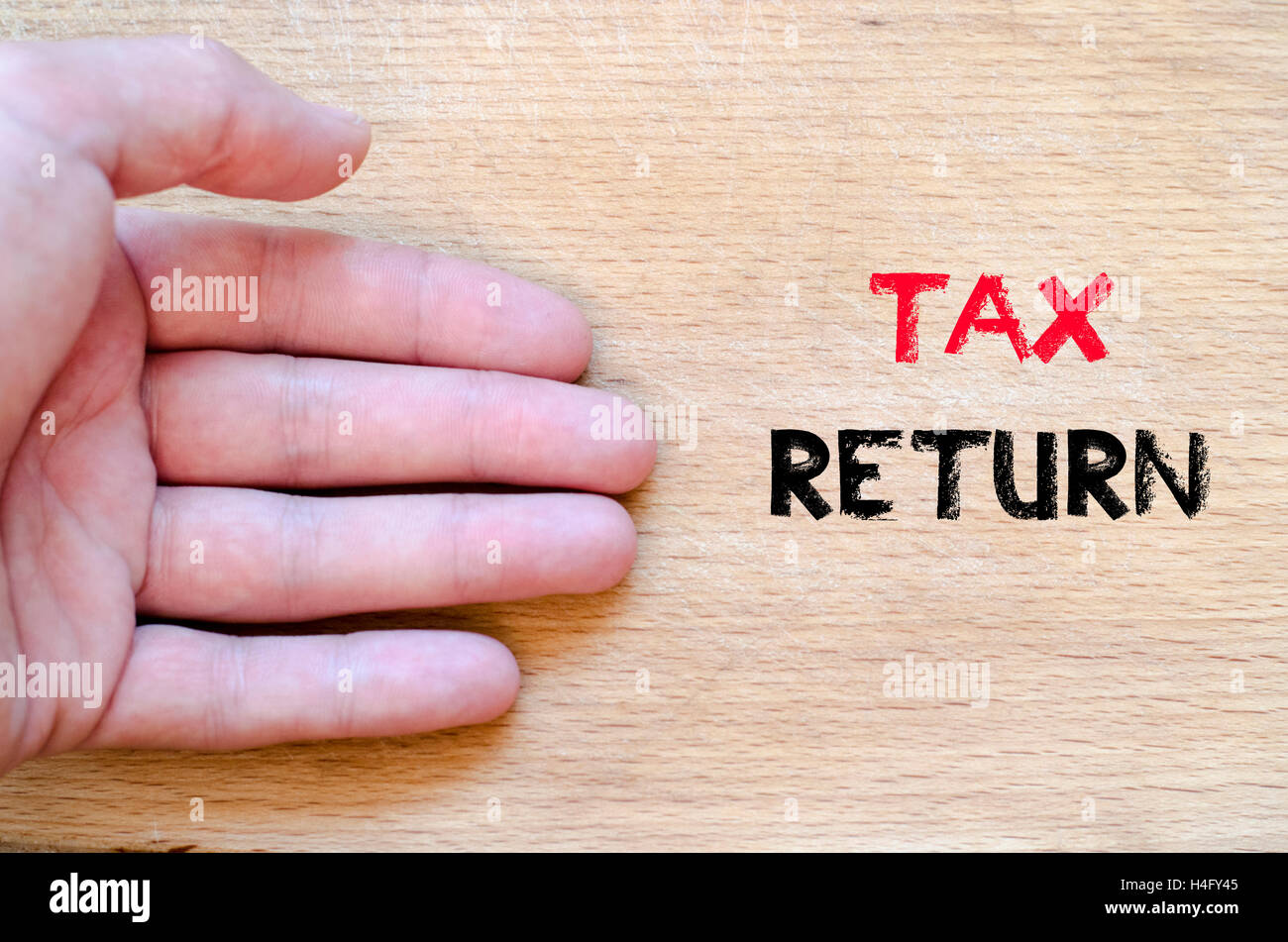 Human hand over wooden background and tax return text concept Stock ...
