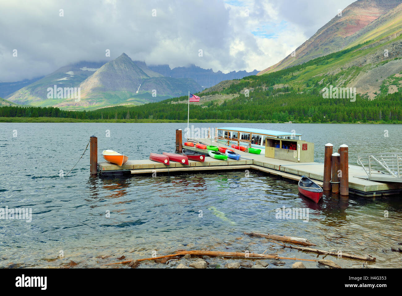 boat and kayaks in swiftcurrent lake in Glacier National Park in summer ...