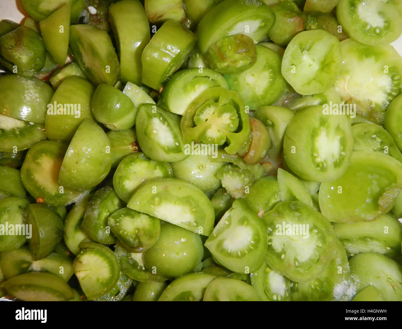 Heap of cut small green tomatoes, background Stock Photo - Alamy