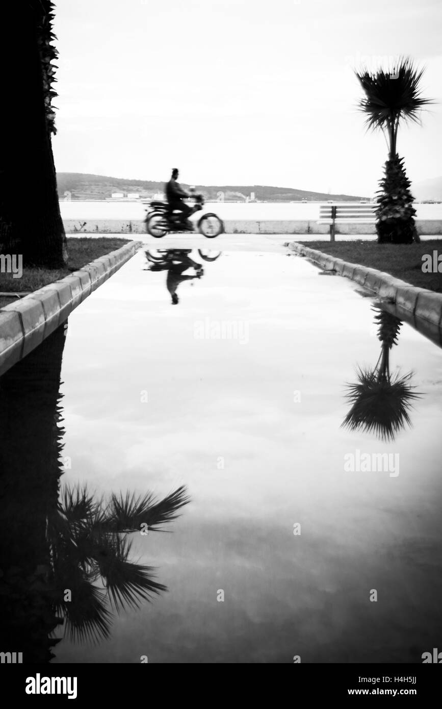 The man riding a motorcycle and his reflection on the water Stock Photo ...
