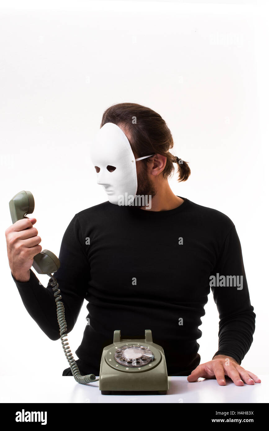The man with mask talking with an old phone.Its an anonymous phone call ...