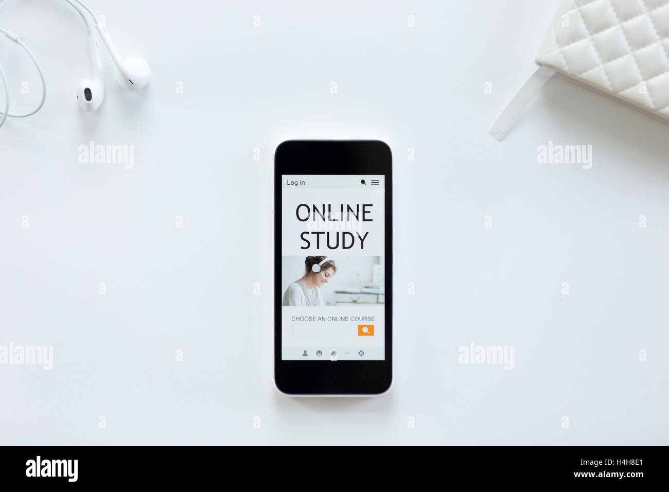 White office desk with earphones, mobile phone, online study on screen ...