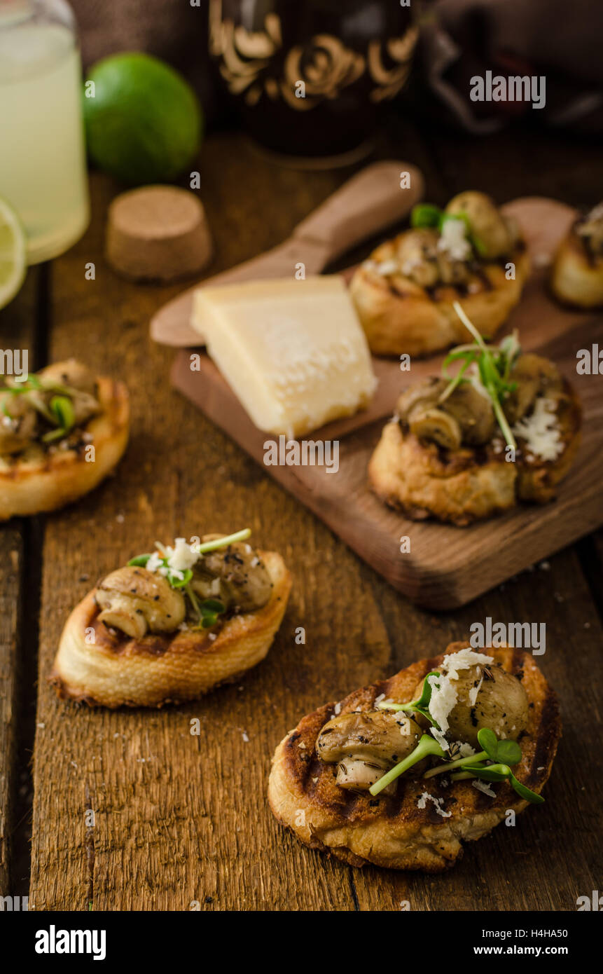 Mushroom snacks on grilled baguette, topped with parmesan cheese and ...