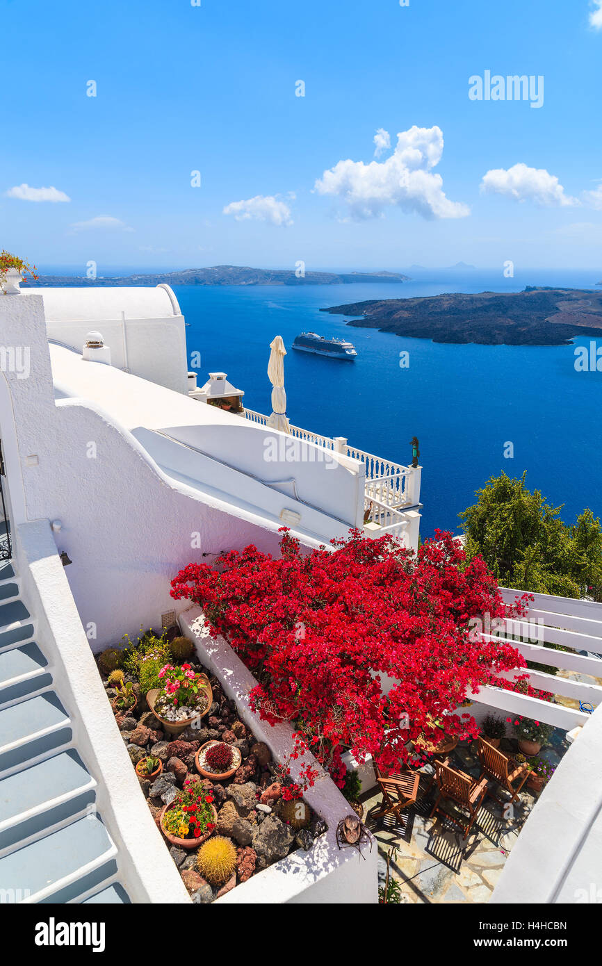 A view of caldera and typical red flowers on terrace of a house in ...