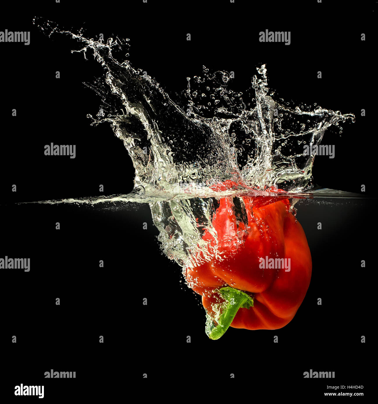 Red bell pepper falling in water on black Stock Photo - Alamy