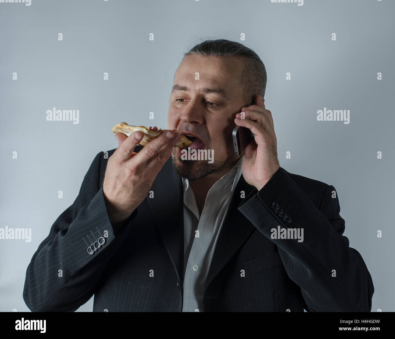 man eating pizza and talking on the phone Stock Photo - Alamy