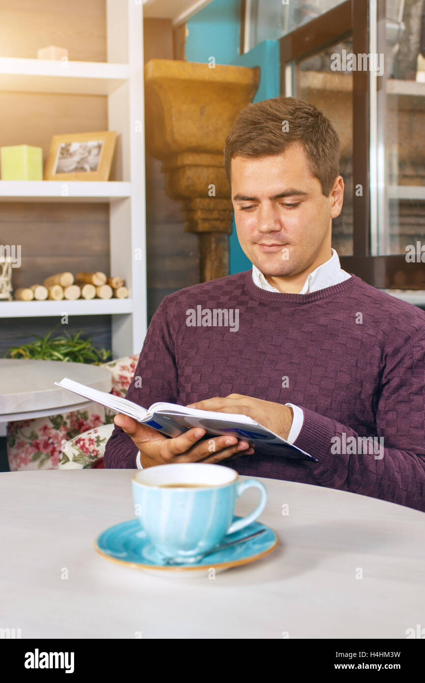 Young man sitting in cafe and reading a book Stock Photo - Alamy
