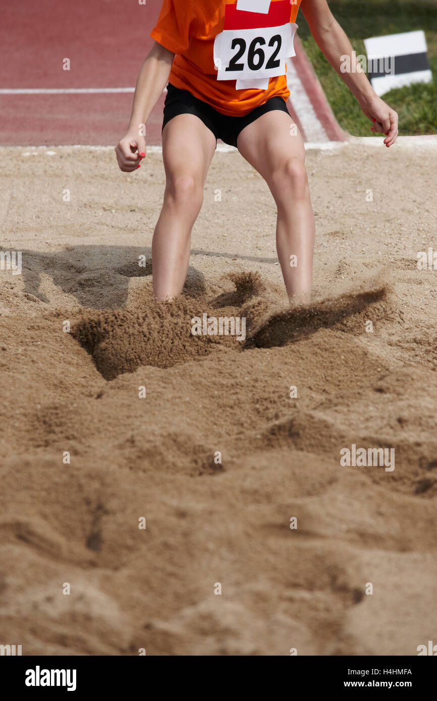 Female long jump competition with woman falling in the sand. Vertical ...