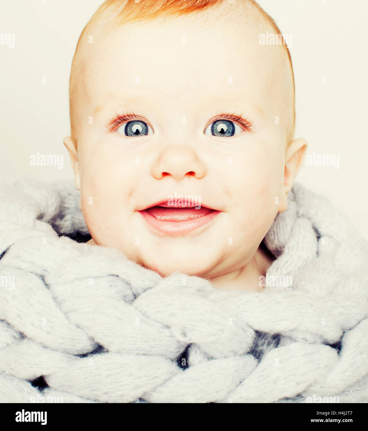 little cute red head baby in scarf all over him close up isolate Stock ...