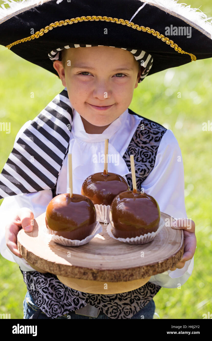 Happy young boy dressed up in pirate Halloween costume and holding tray ...
