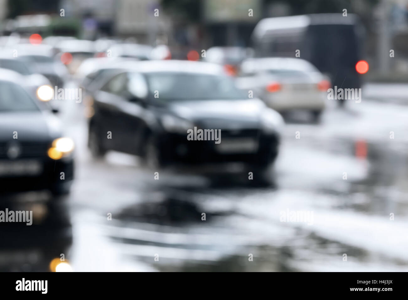 stream of cars on street road with water puddles during heavy rain ...