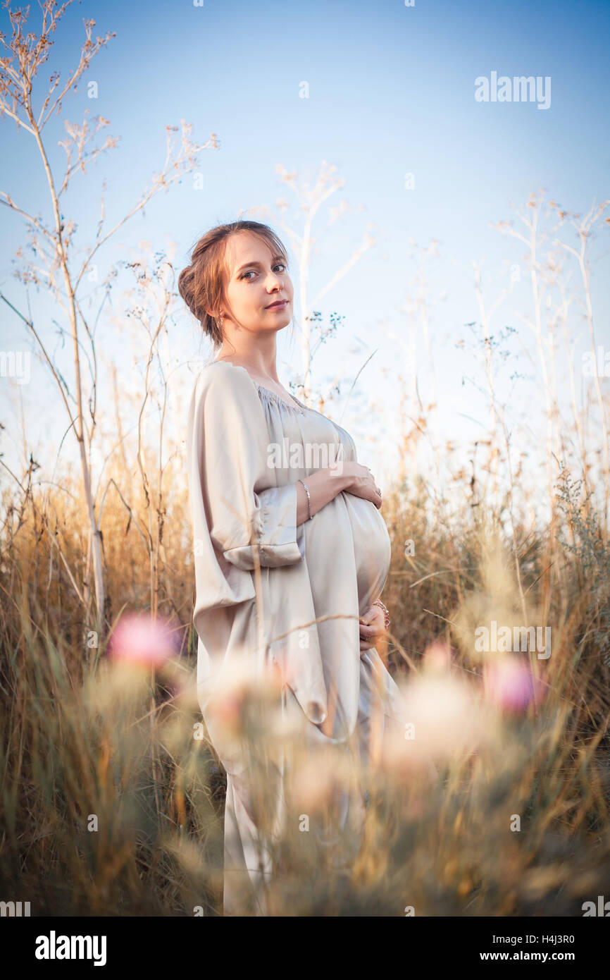 Portrait of a pregnant woman in the sunset light on the nature of the ...