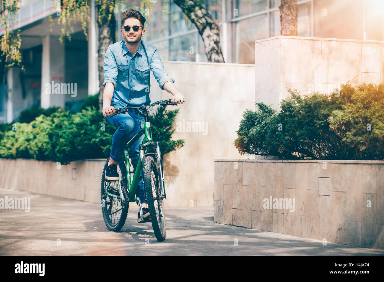 Positive smiling guy riding a bike Stock Photo - Alamy